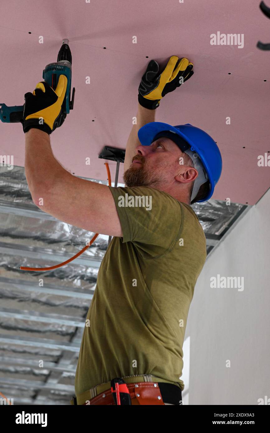 Construction worker wearing protective gear using power drill to ...