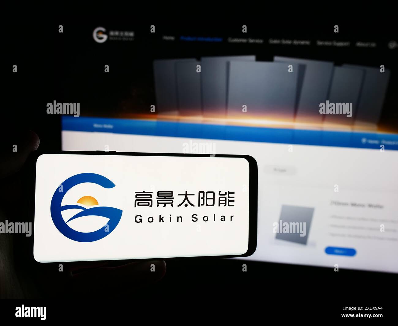 Person holding mobile phone with logo of Chinese photovoltaics company ...