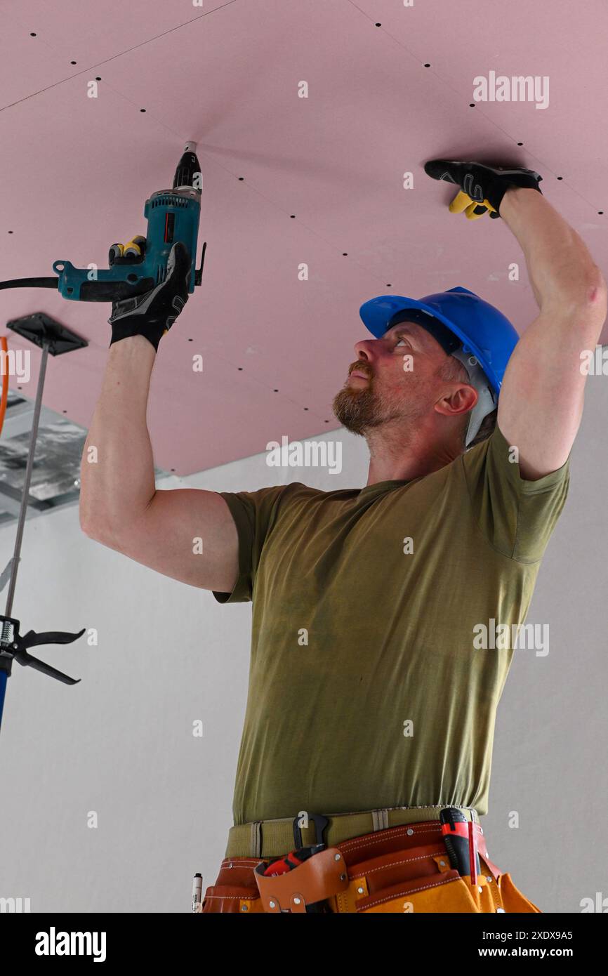 Construction worker wearing protective gear using power drill to ...