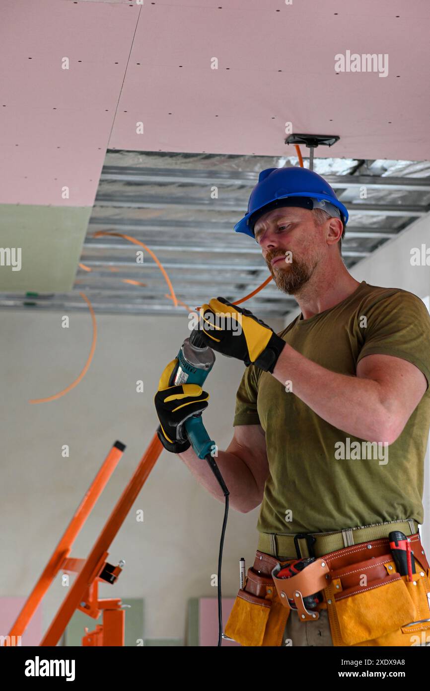 Construction worker wearing tool belt and safety equipment using power ...