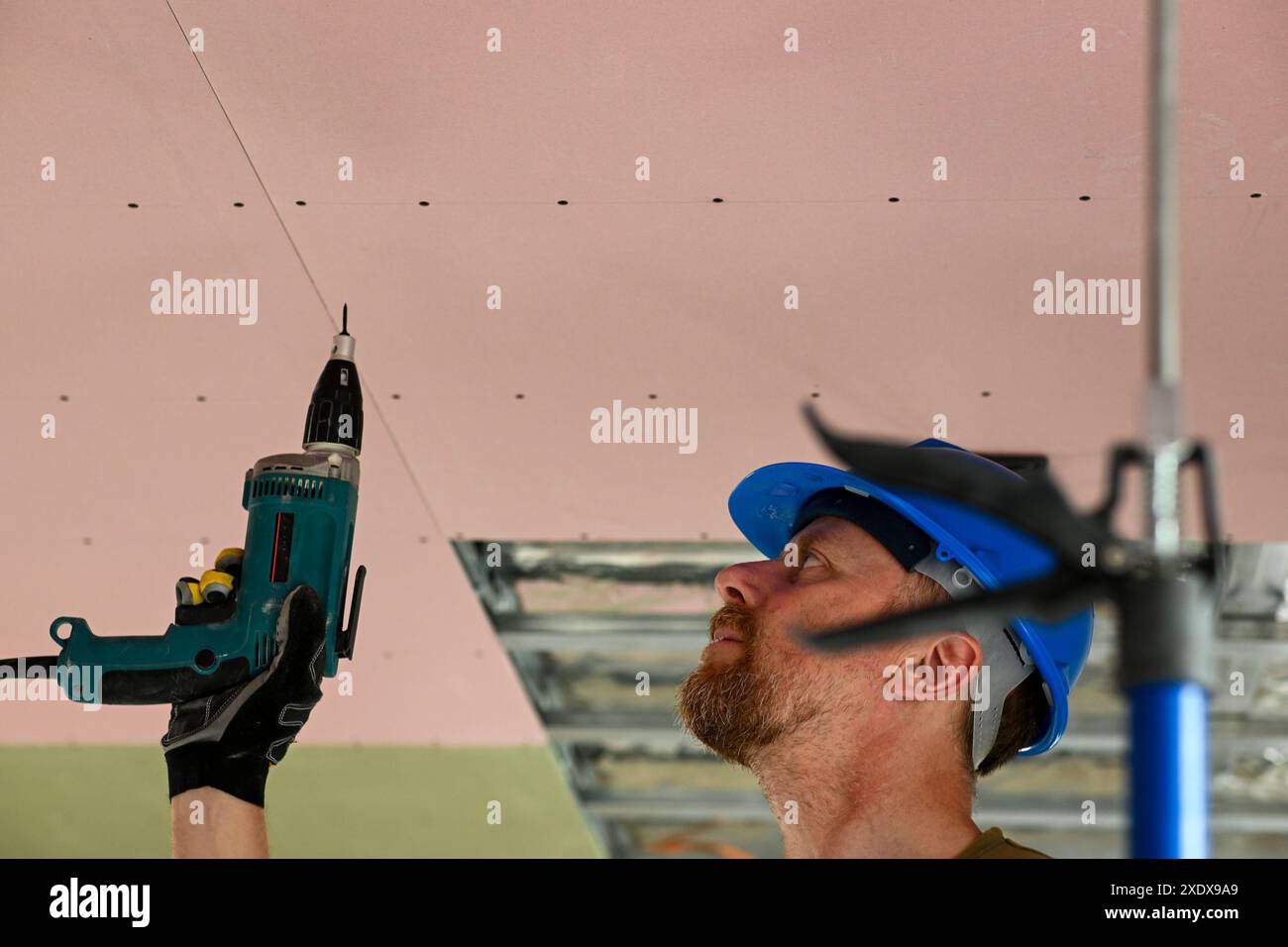 Construction worker wearing protective gear using power drill to ...