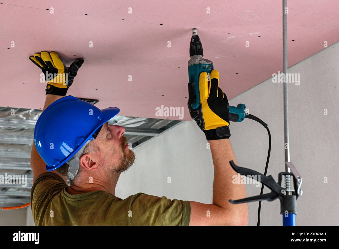 Construction worker wearing protective gear using power drill to ...