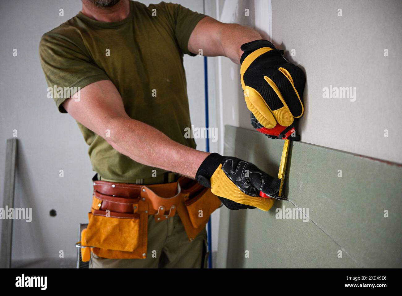 Construction worker wearing tool belt and hard hat measuring ...