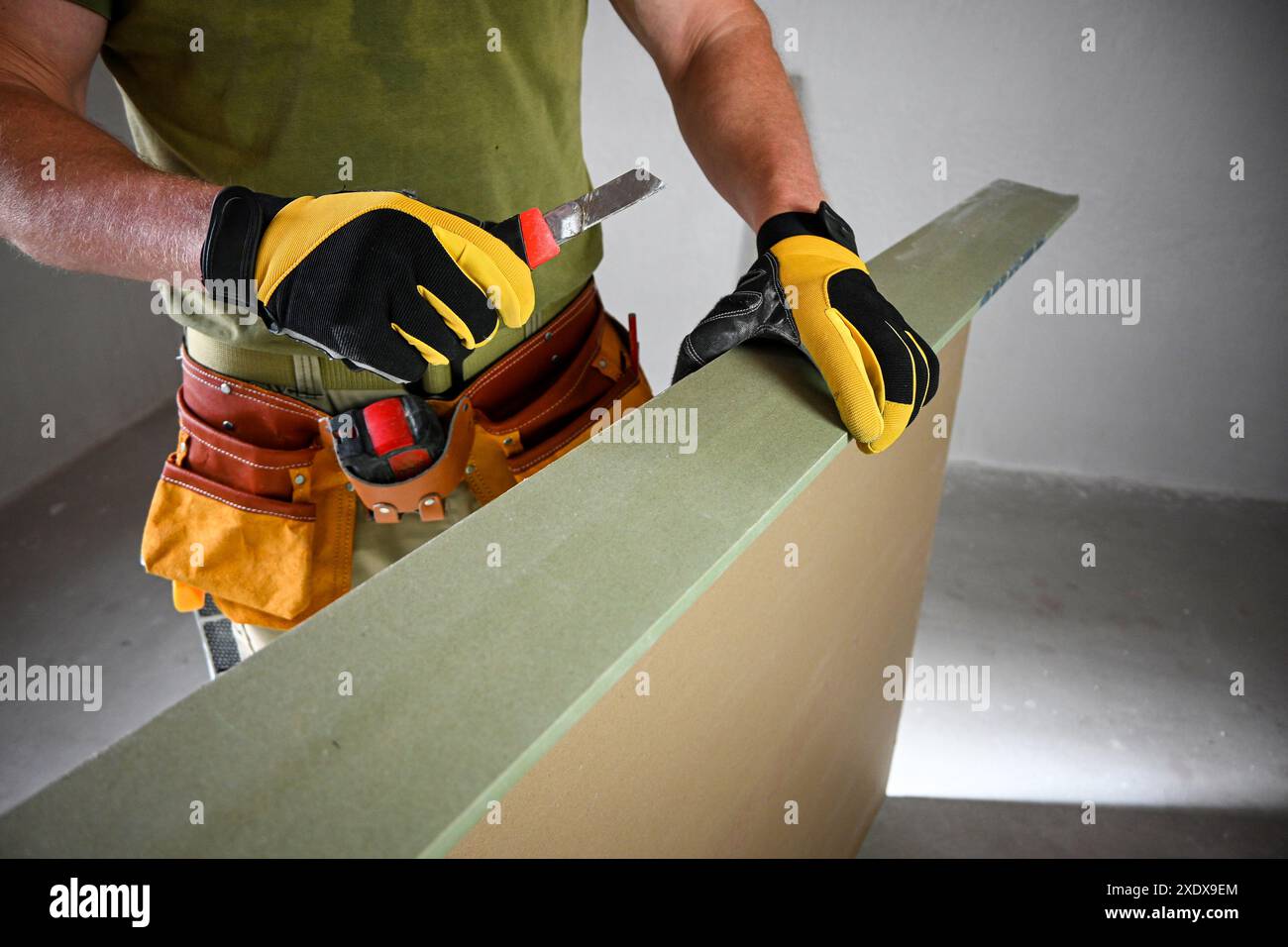 Construction worker wearing tool belt and holding drywall and utility ...