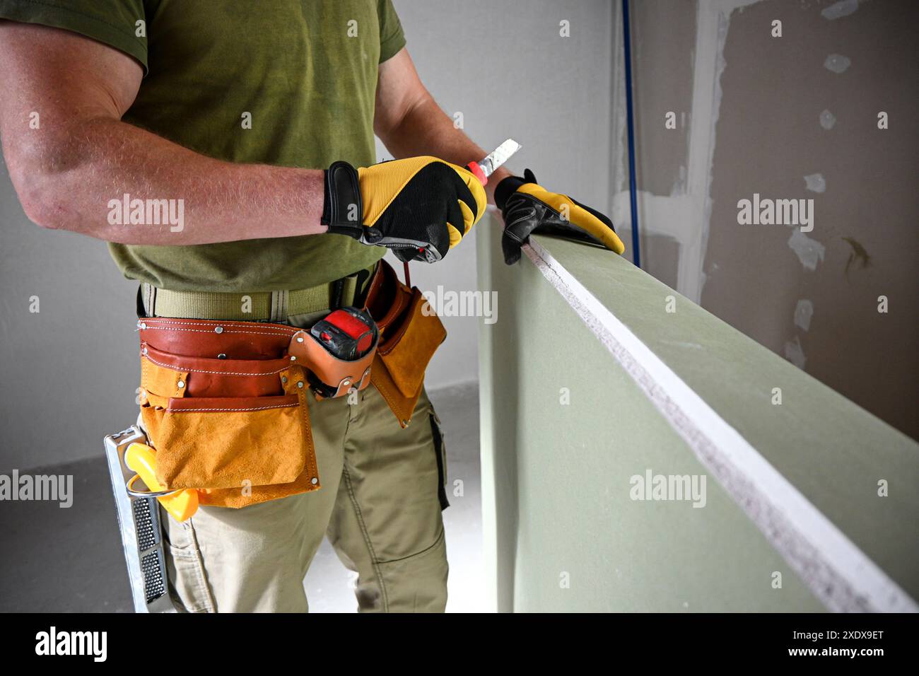 Construction worker wearing tool belt and holding drywall and utility ...