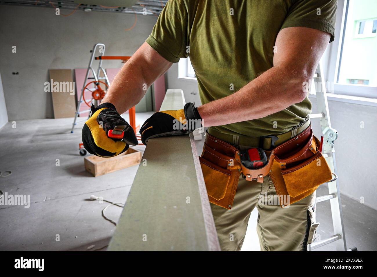 Construction worker wearing tool belt and holding drywall and utility ...
