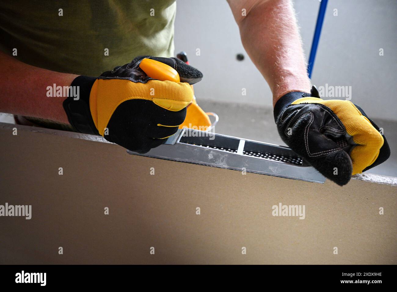 Construction worker wearing protective gloves sanding drywall using ...