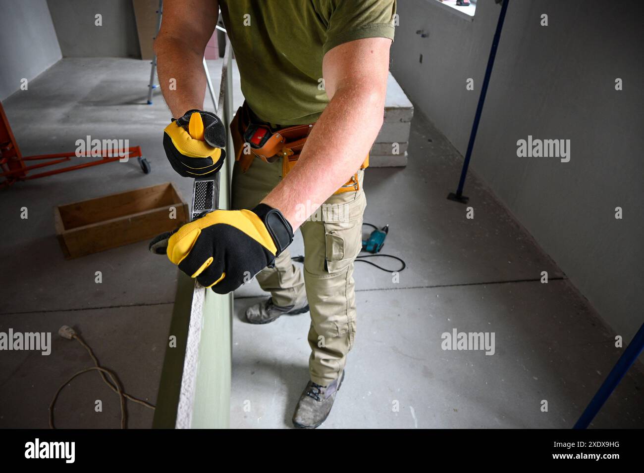 Construction worker wearing protective gloves sanding drywall using ...