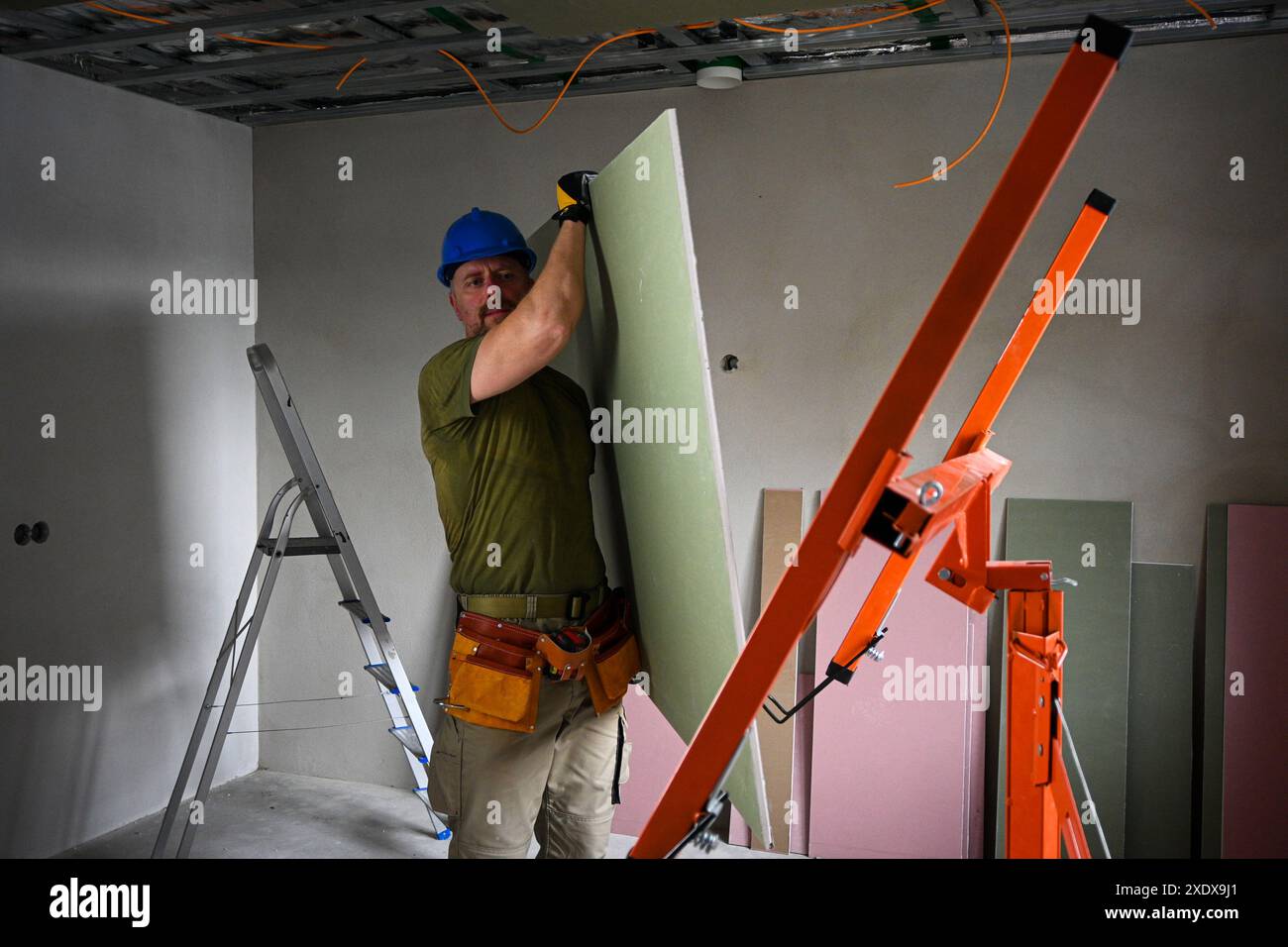 Construction worker carrying a large plasterboard with the help of a ...