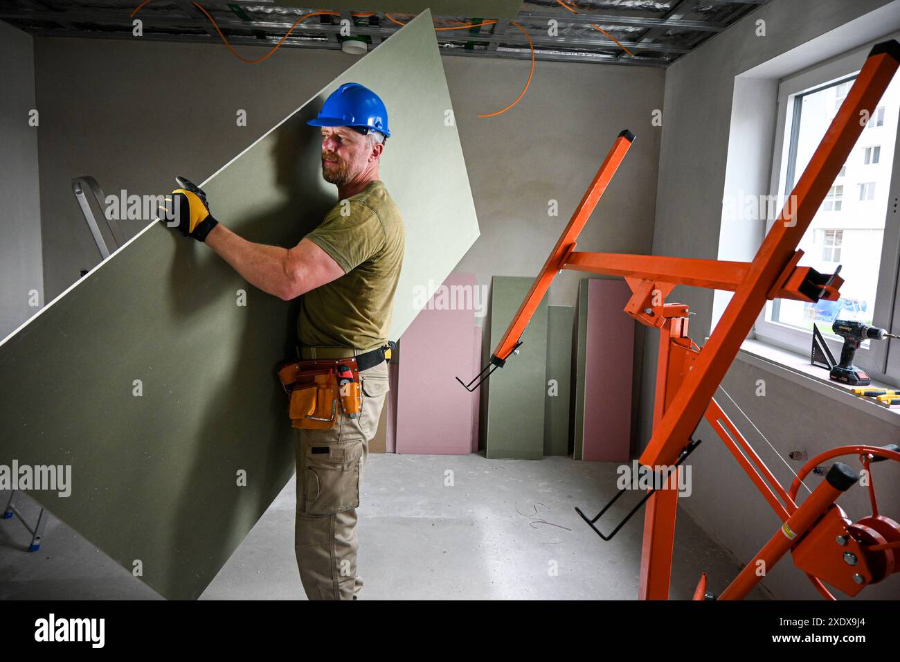 Construction worker carrying a large plasterboard with the help of a ...