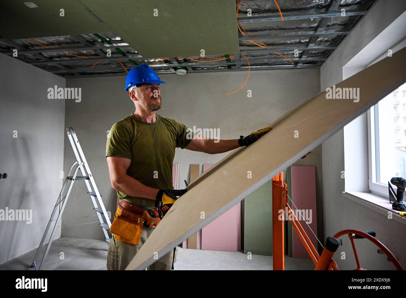 Construction worker carrying a large plasterboard with the help of a ...