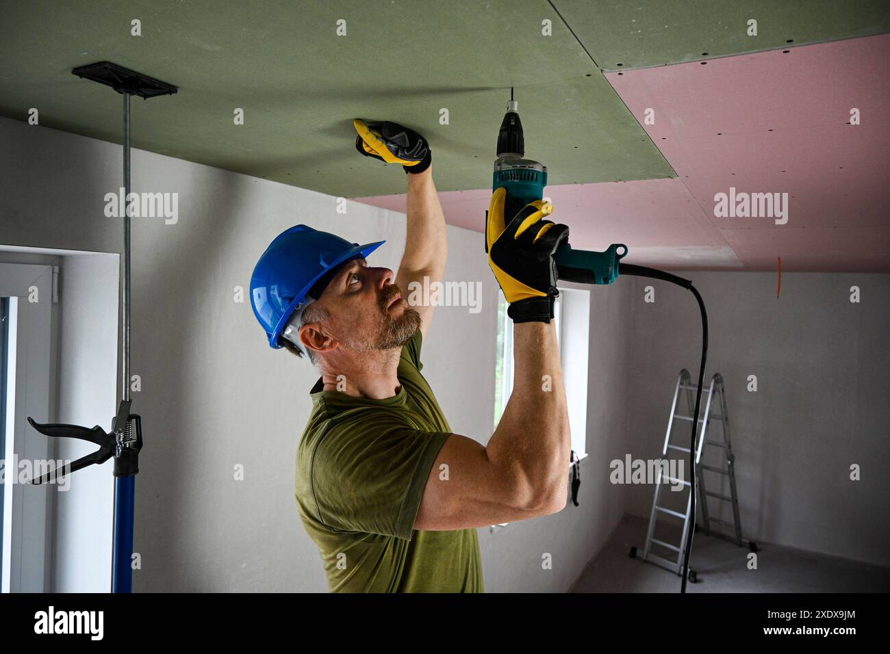 Construction worker wearing protective gear using power drill to ...