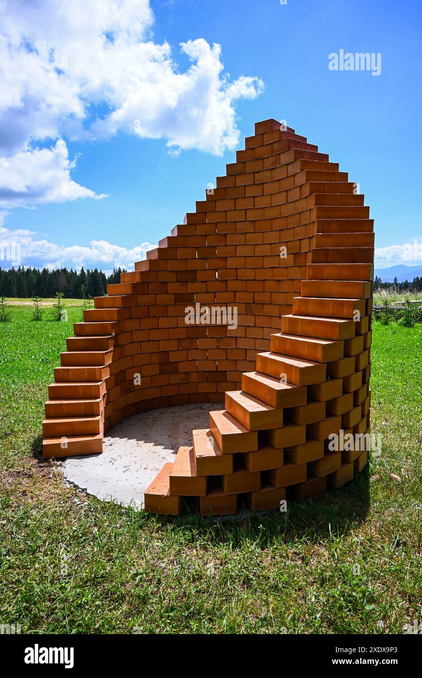 A spiral of bricks standing in a grassy field, creating a unique ...