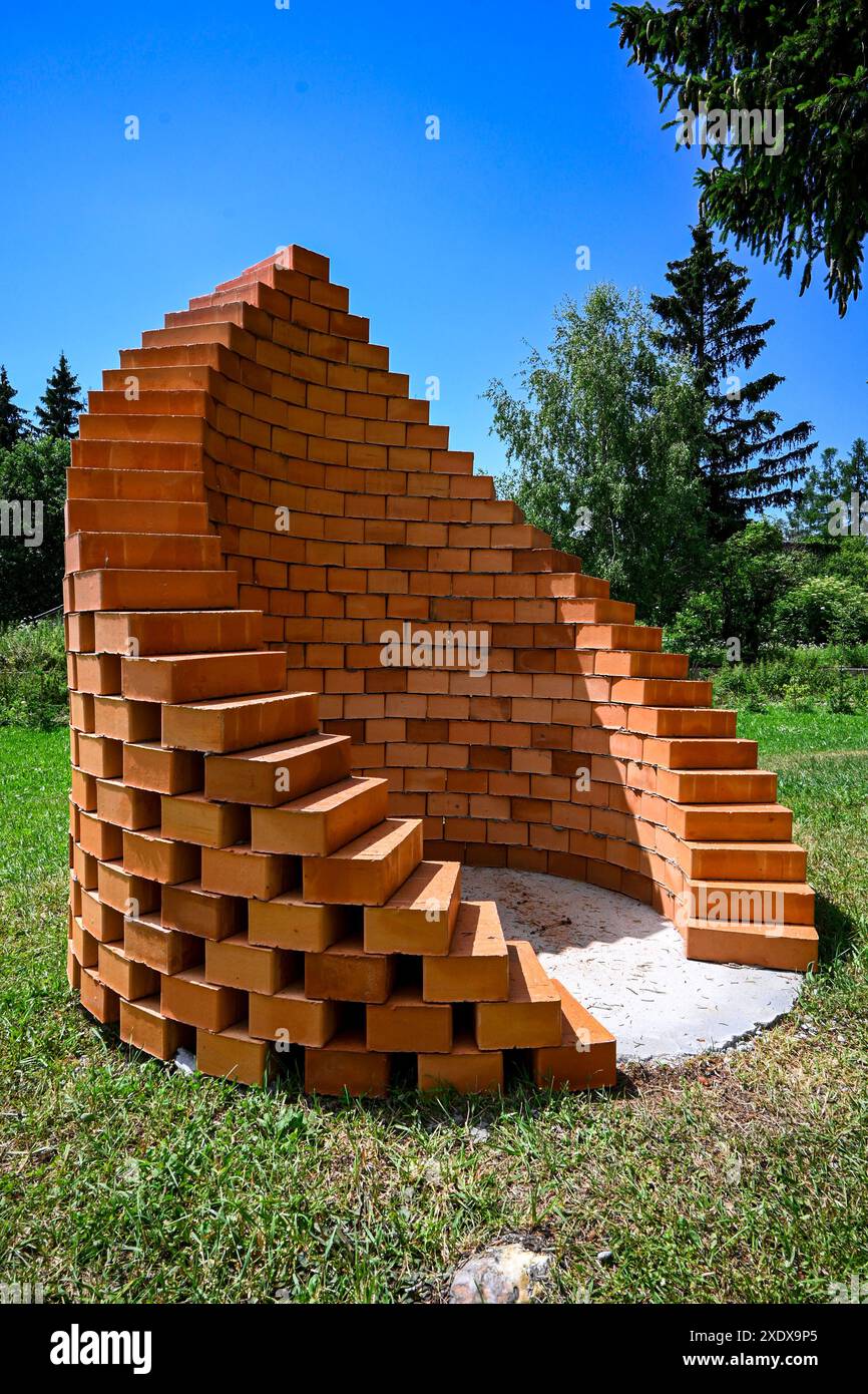 A spiral of bricks standing in a grassy field, creating a unique ...