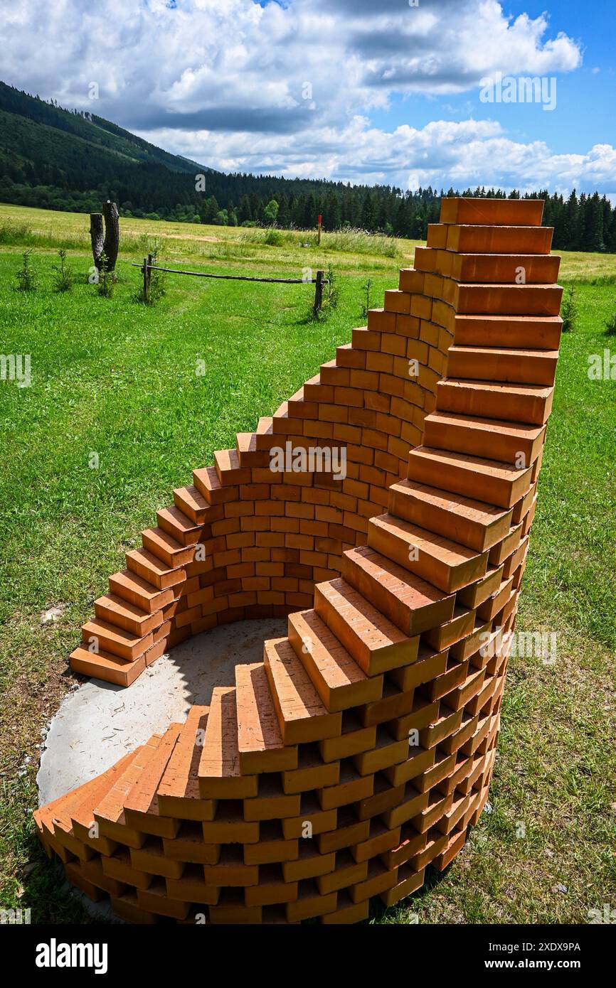 A spiral of bricks standing in a grassy field, creating a unique ...