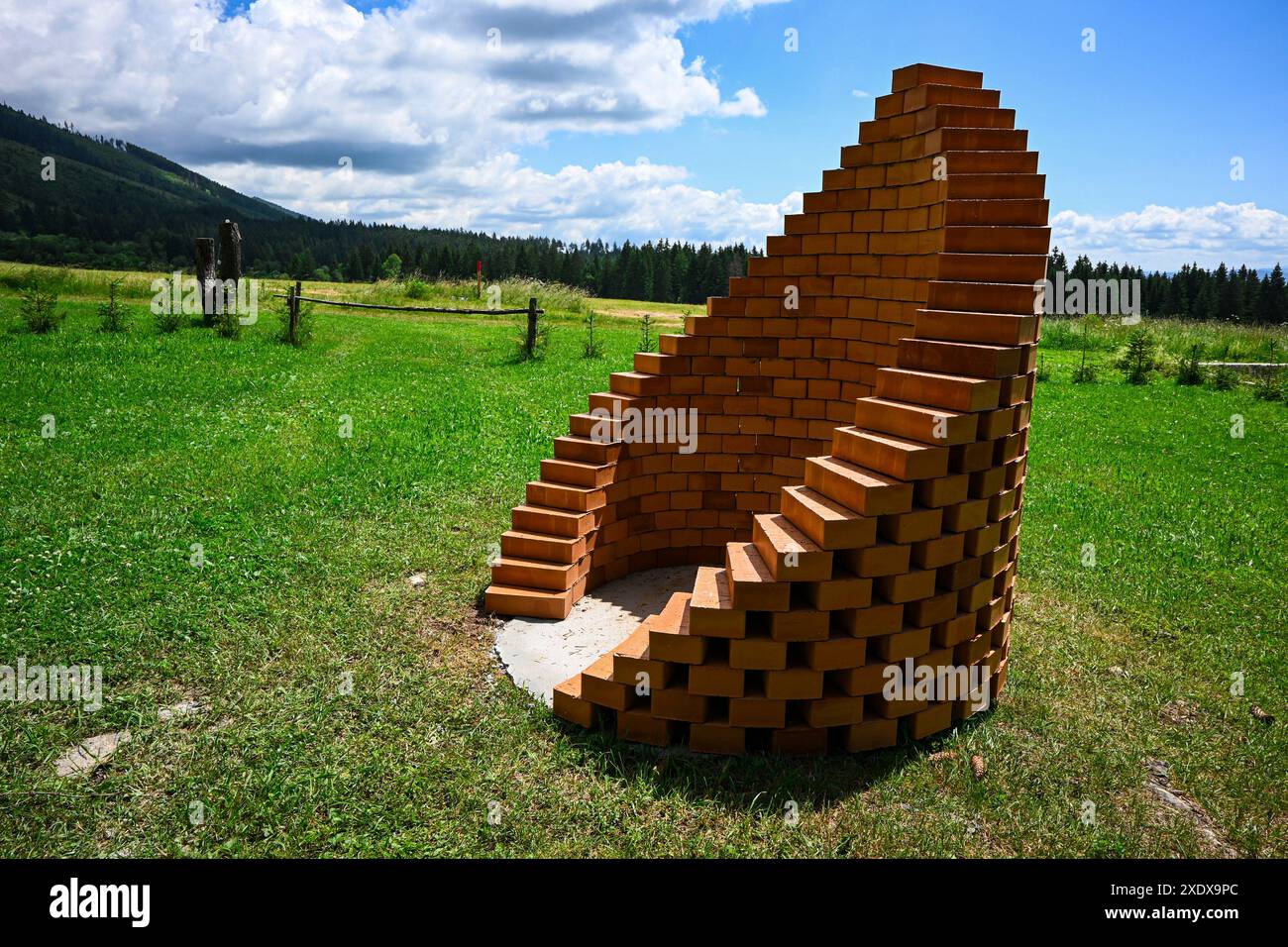 A spiral of bricks standing in a grassy field, creating a unique ...