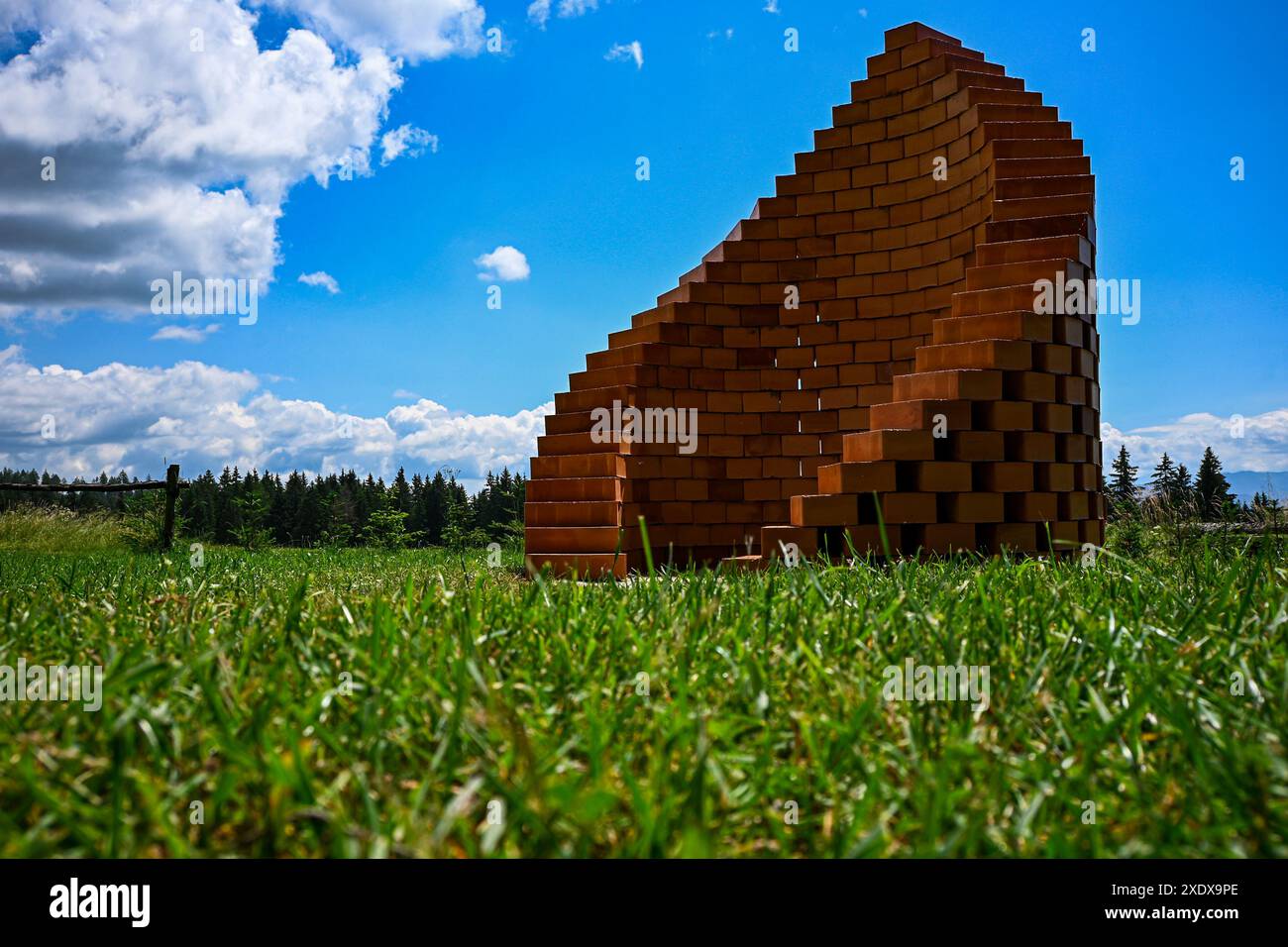 A spiral of bricks standing in a grassy field, creating a unique ...