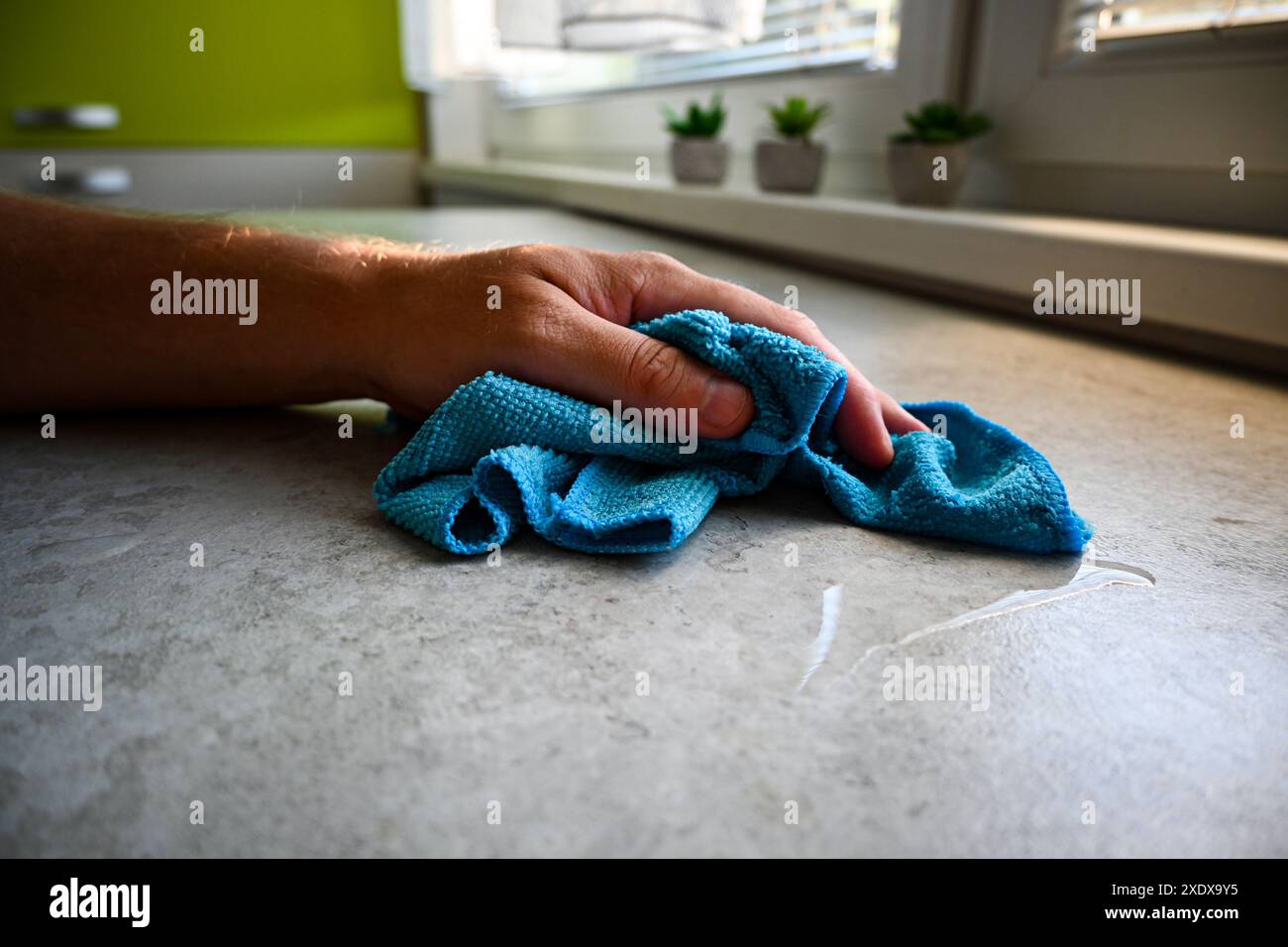 Person is wiping up a spill on a kitchen counter with a blue microfiber ...