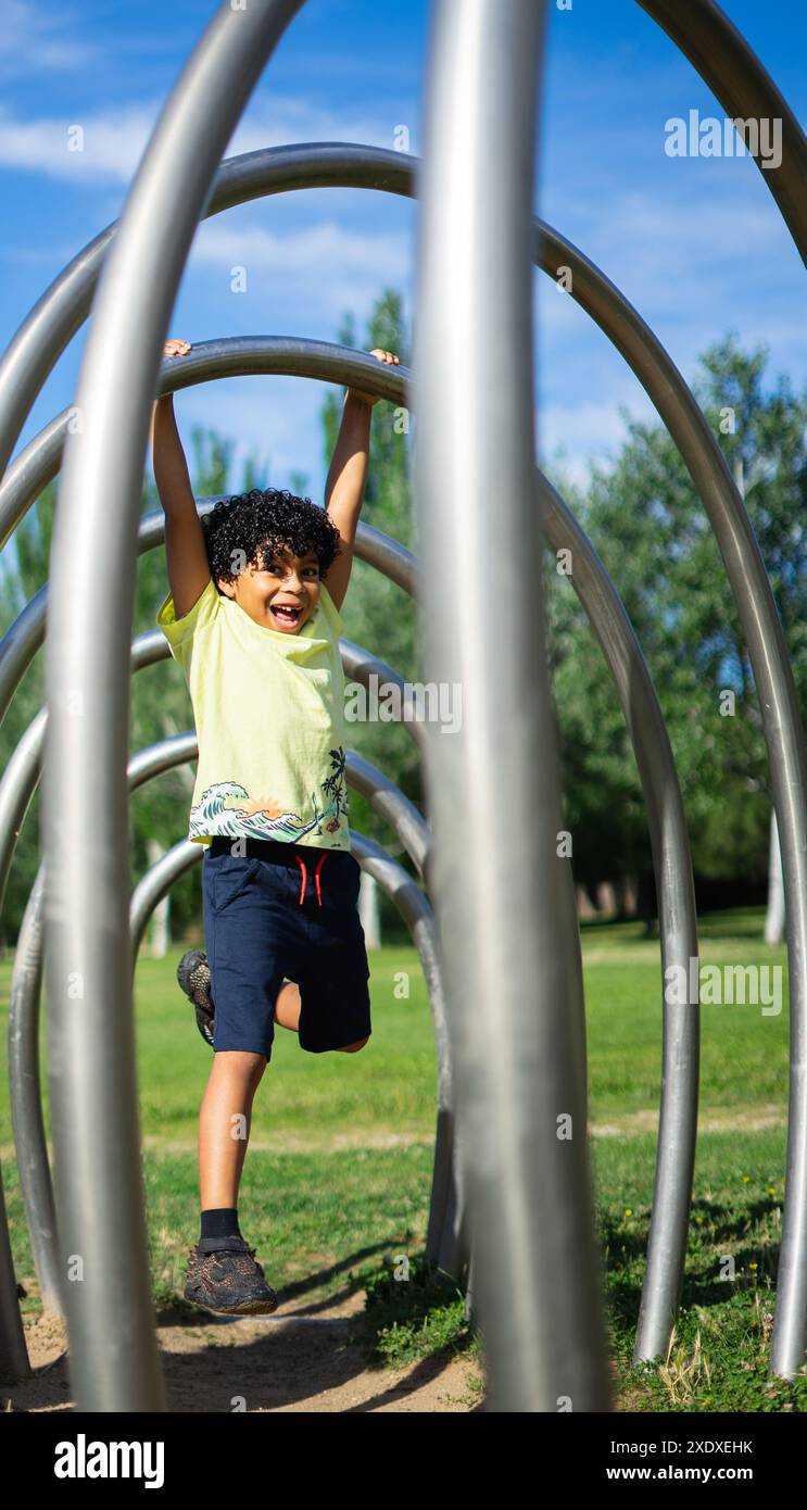 8 year old Latino boy playing in a park hanging from a structure Stock ...