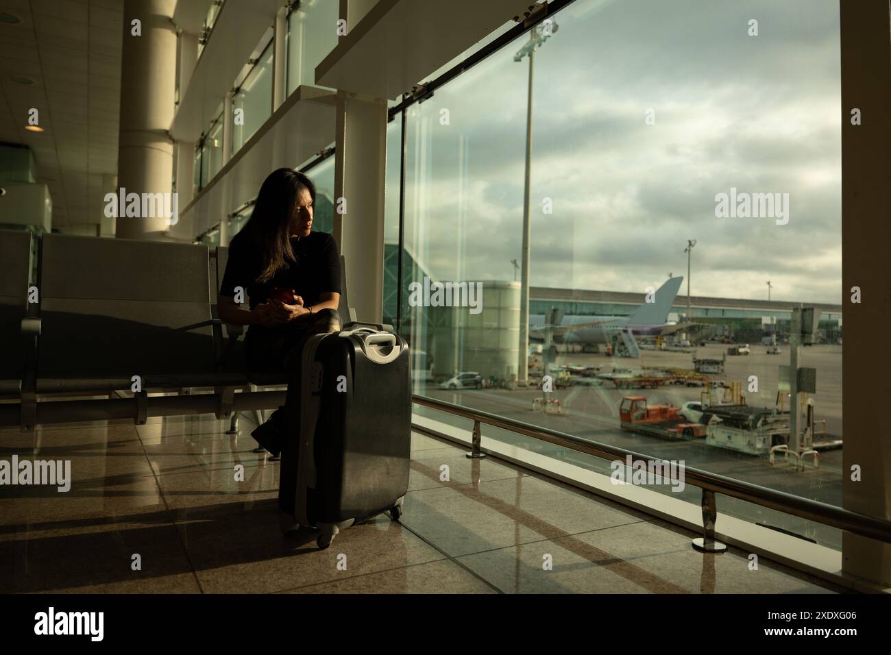 A woman in the airport boarding area, waits for her flight watching the ...