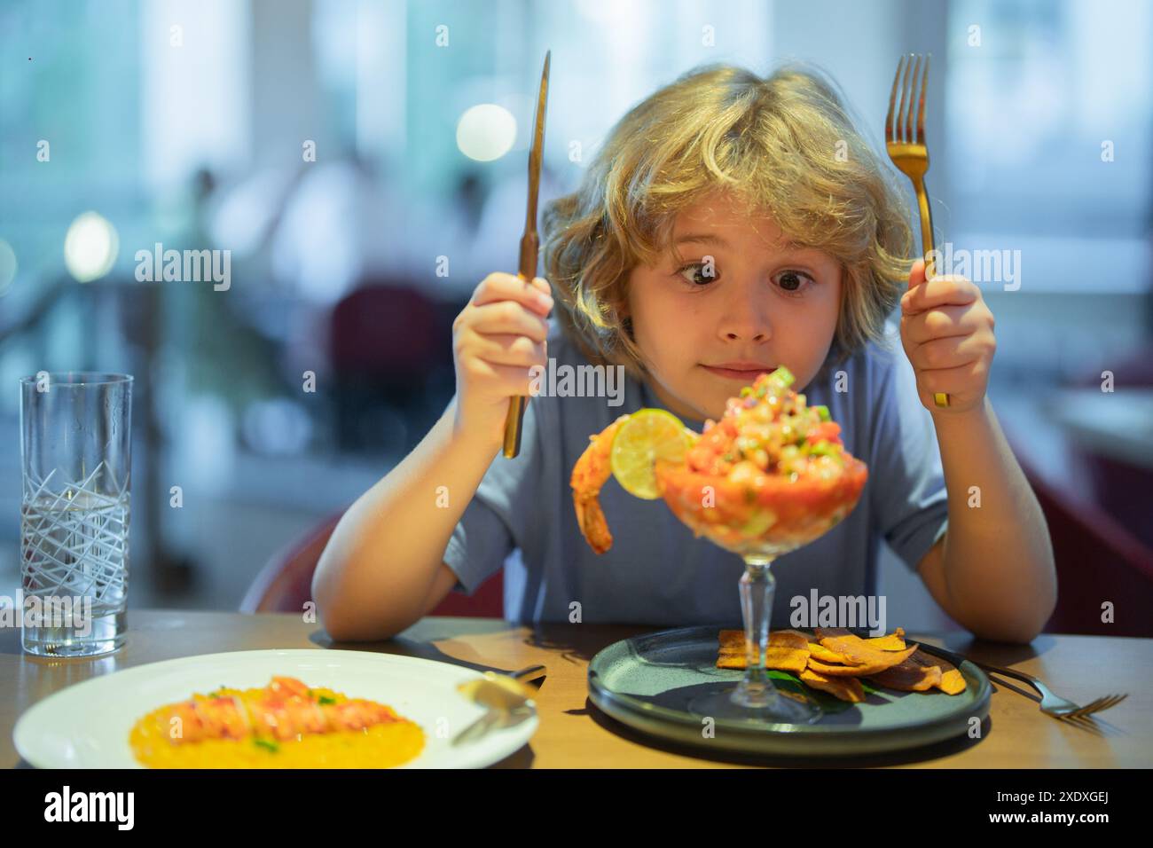 Funny surprised Little boy eating seafood in cafe. Kid eat Food fish ...
