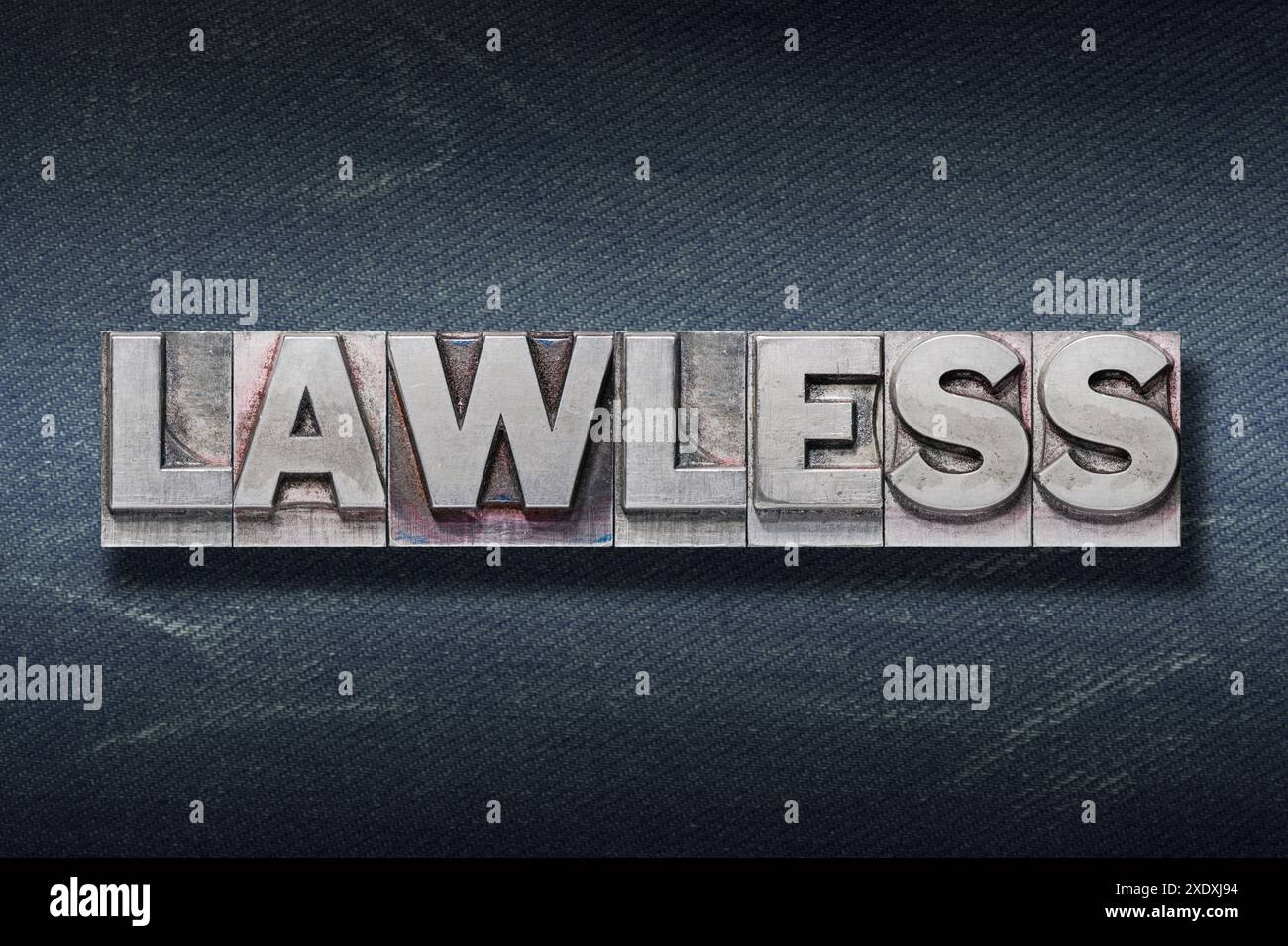 lawless word made from metallic letterpress on dark jeans background ...