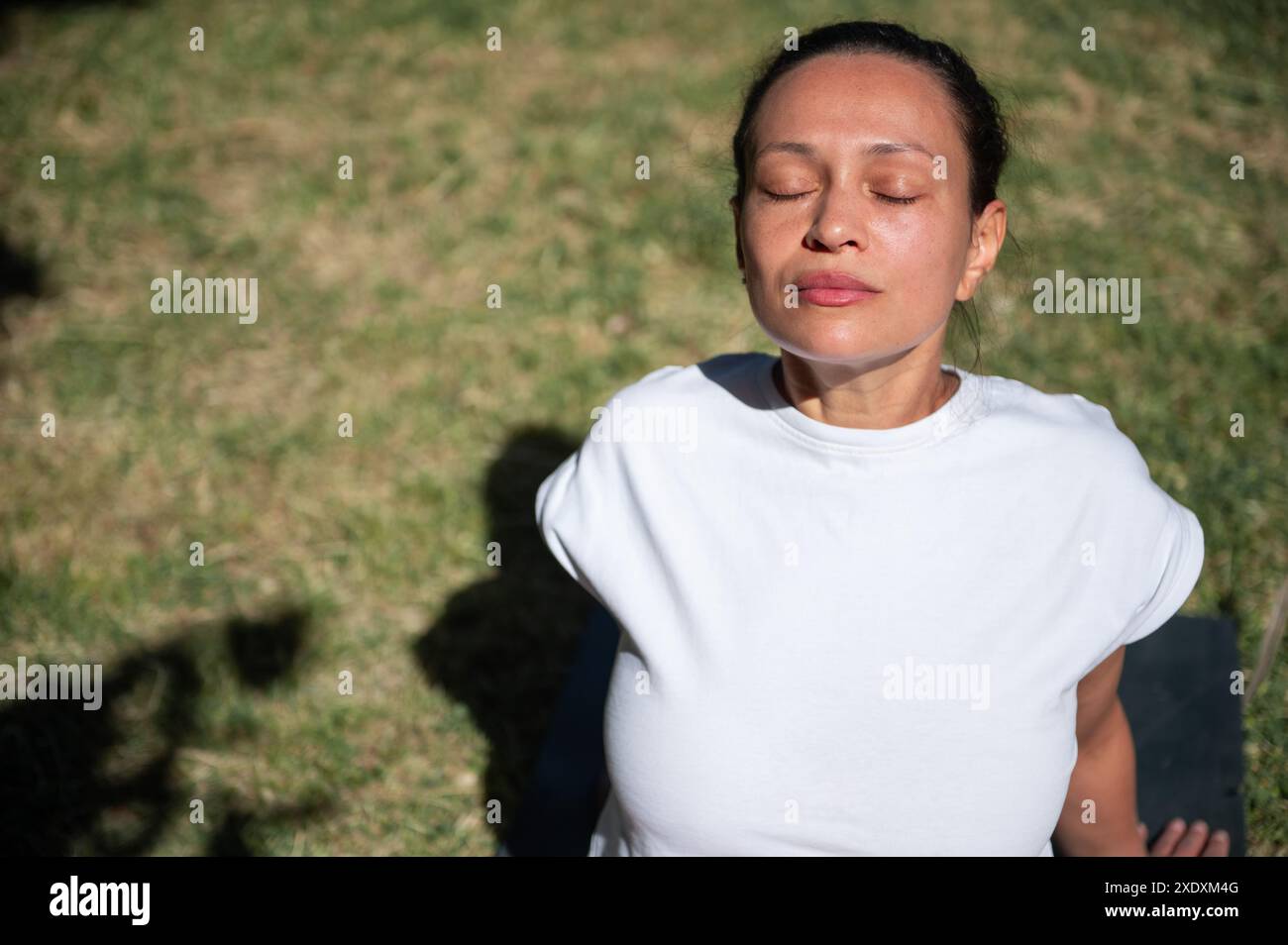 Calm woman meditating outside in a park, feeling relaxed and peaceful ...