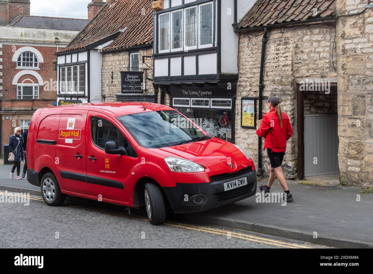Postwoman and red Royal Mail van delivering mail in Pickering town ...