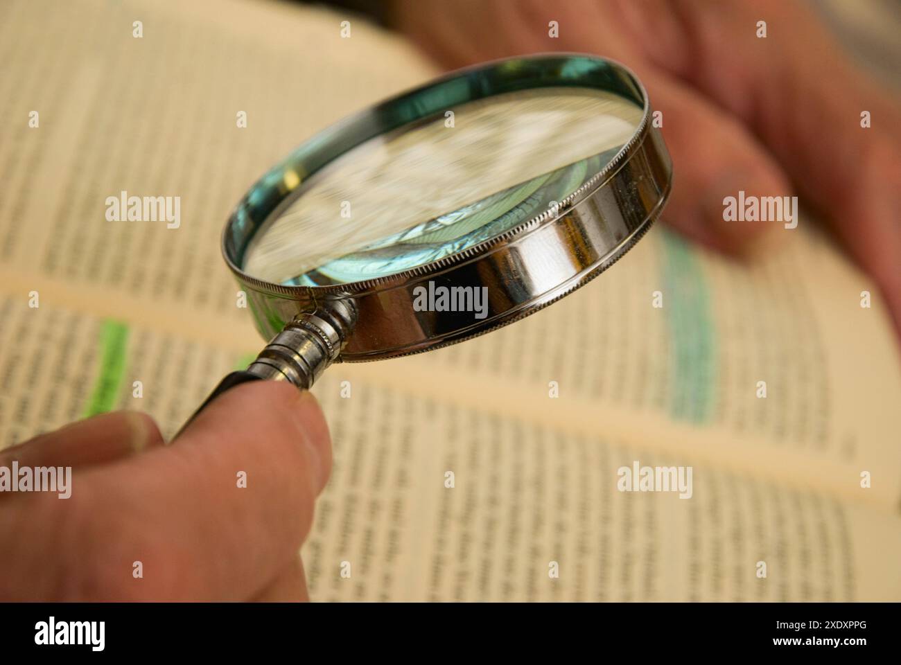 An elderly man lists a book with a magnifying glass Stock Photo - Alamy