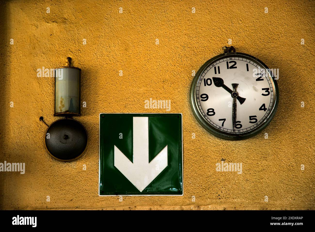 Clock, emergency exit arrow and bell on the wall Stock Photo - Alamy