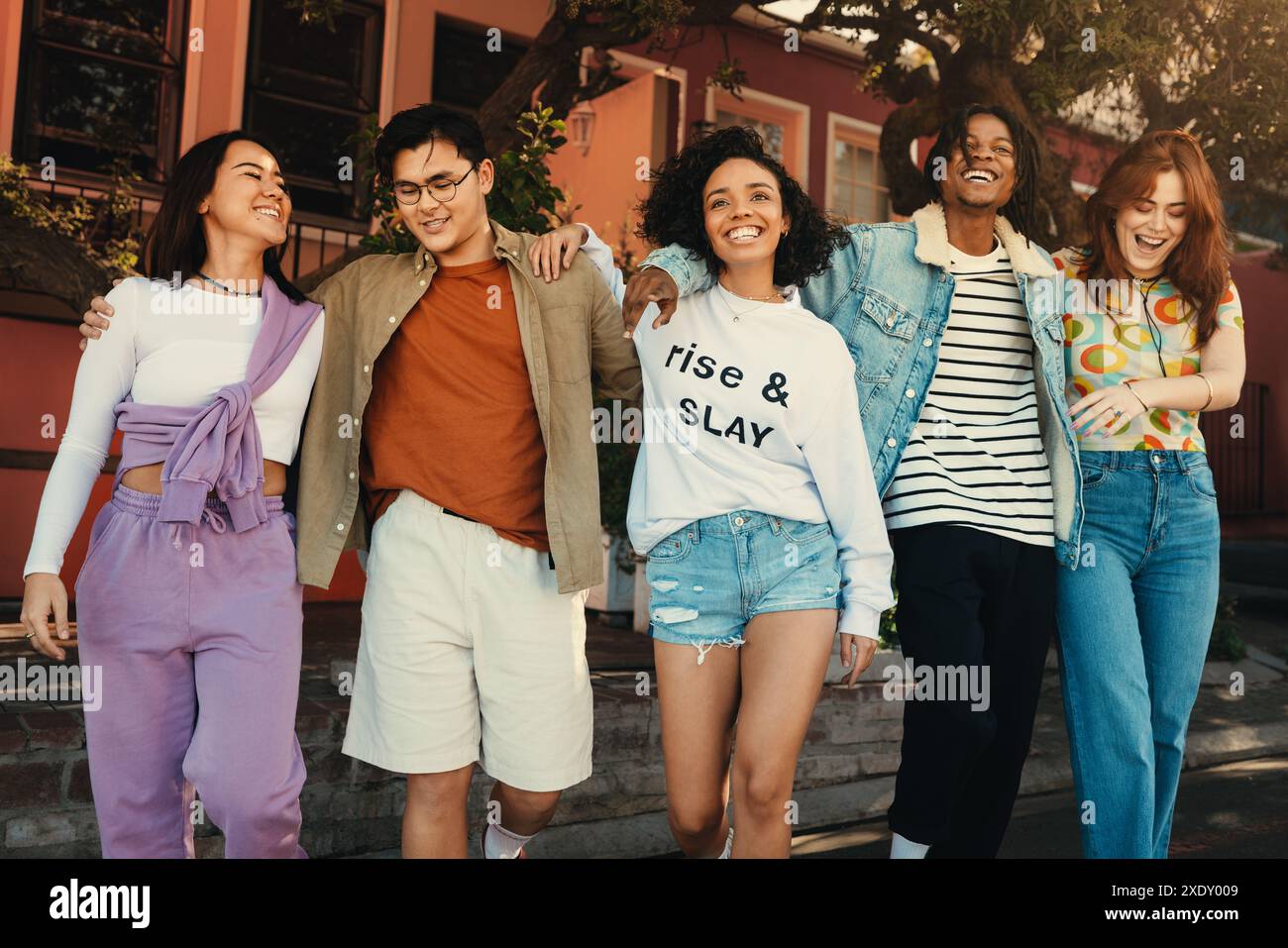 Happy group of friends walking arm in arm in the city, smiling and ...