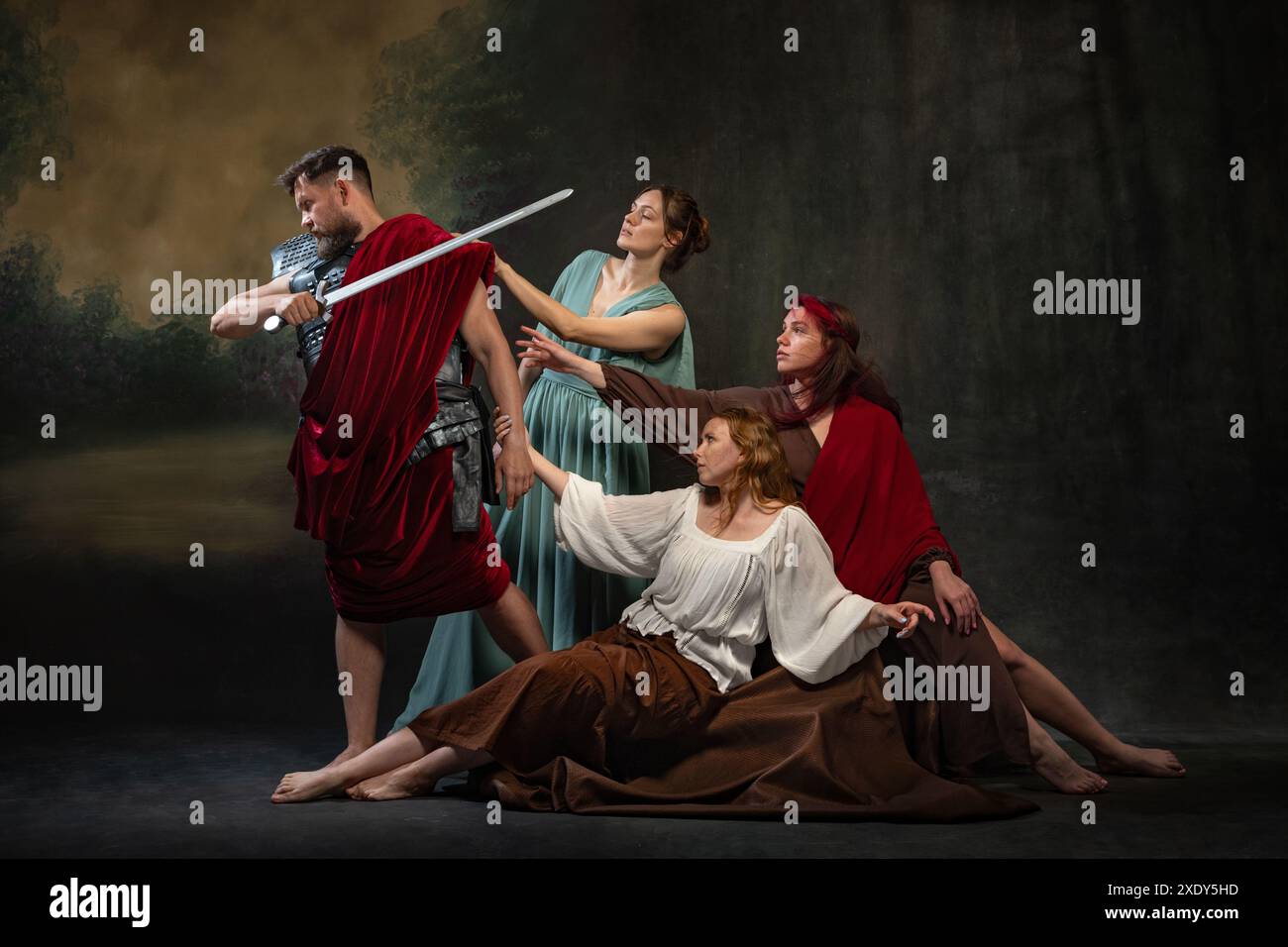 Man in medieval armor and red cloak brandishes sword while three women ...