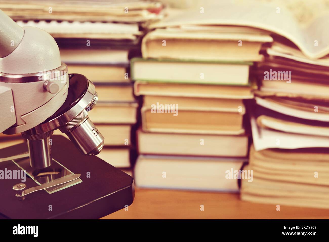 Microscope against a background of books Stock Photo - Alamy