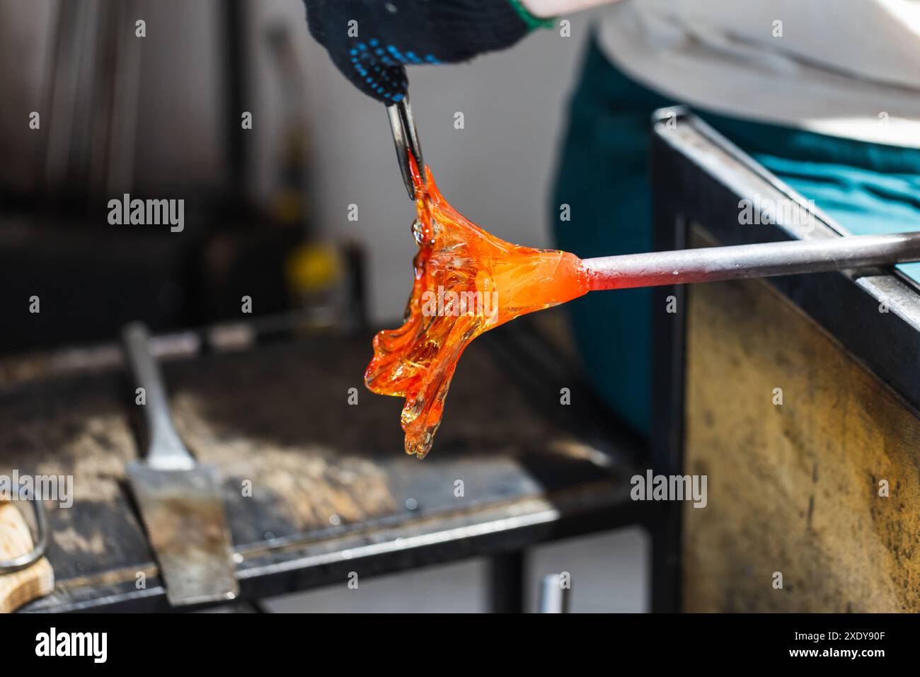 Molding molten glass into a flower shape at glass blowing workshop ...