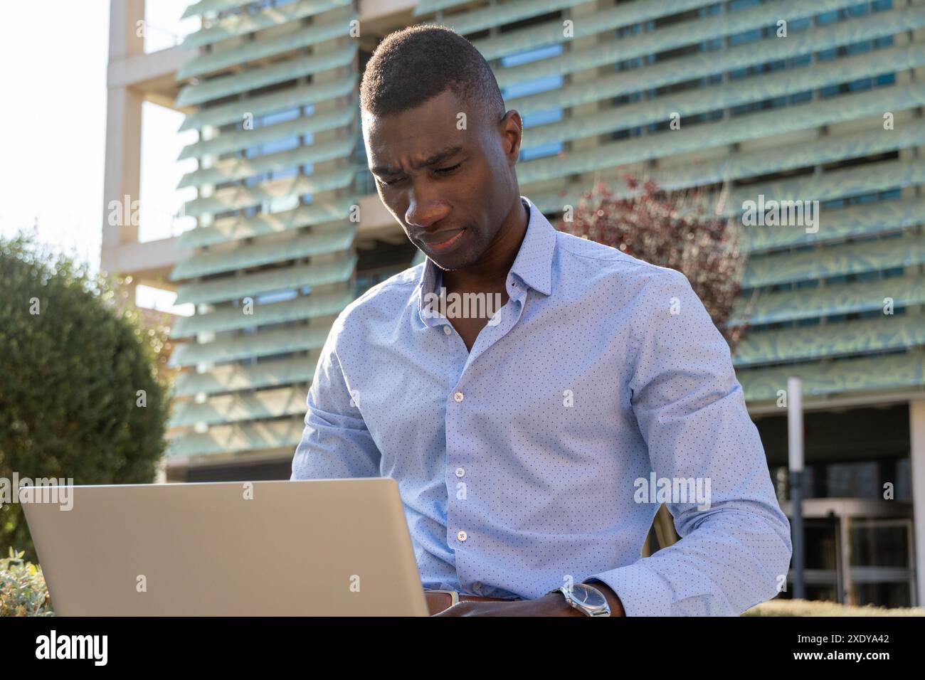 Young African businessman working concentrated with laptop outdoors in ...