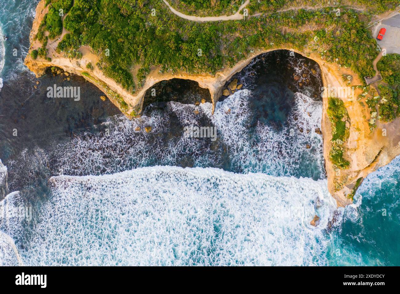 Aerial view of waves breaking into rocky caves eroded into coastal ...