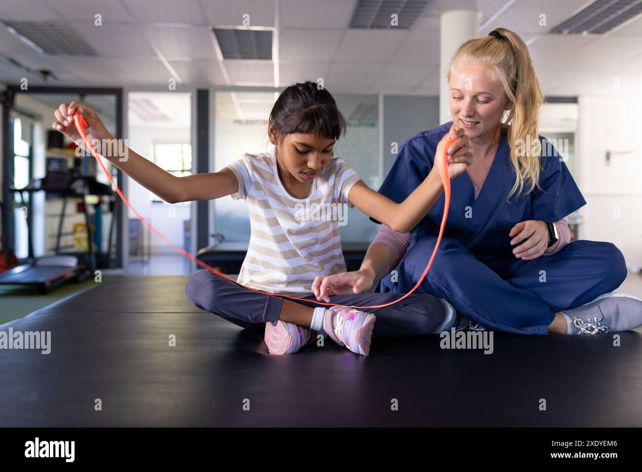 Helping girl with cerebral palsy with resistance band, female therapist ...