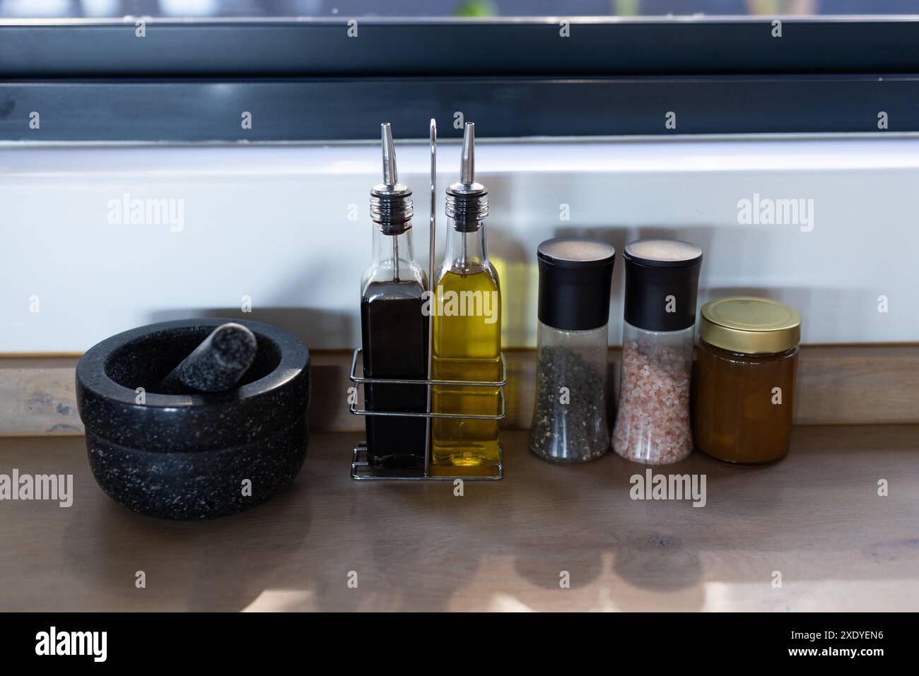 On kitchen counter, mortar and pestle with olive oil, vinegar, salt ...