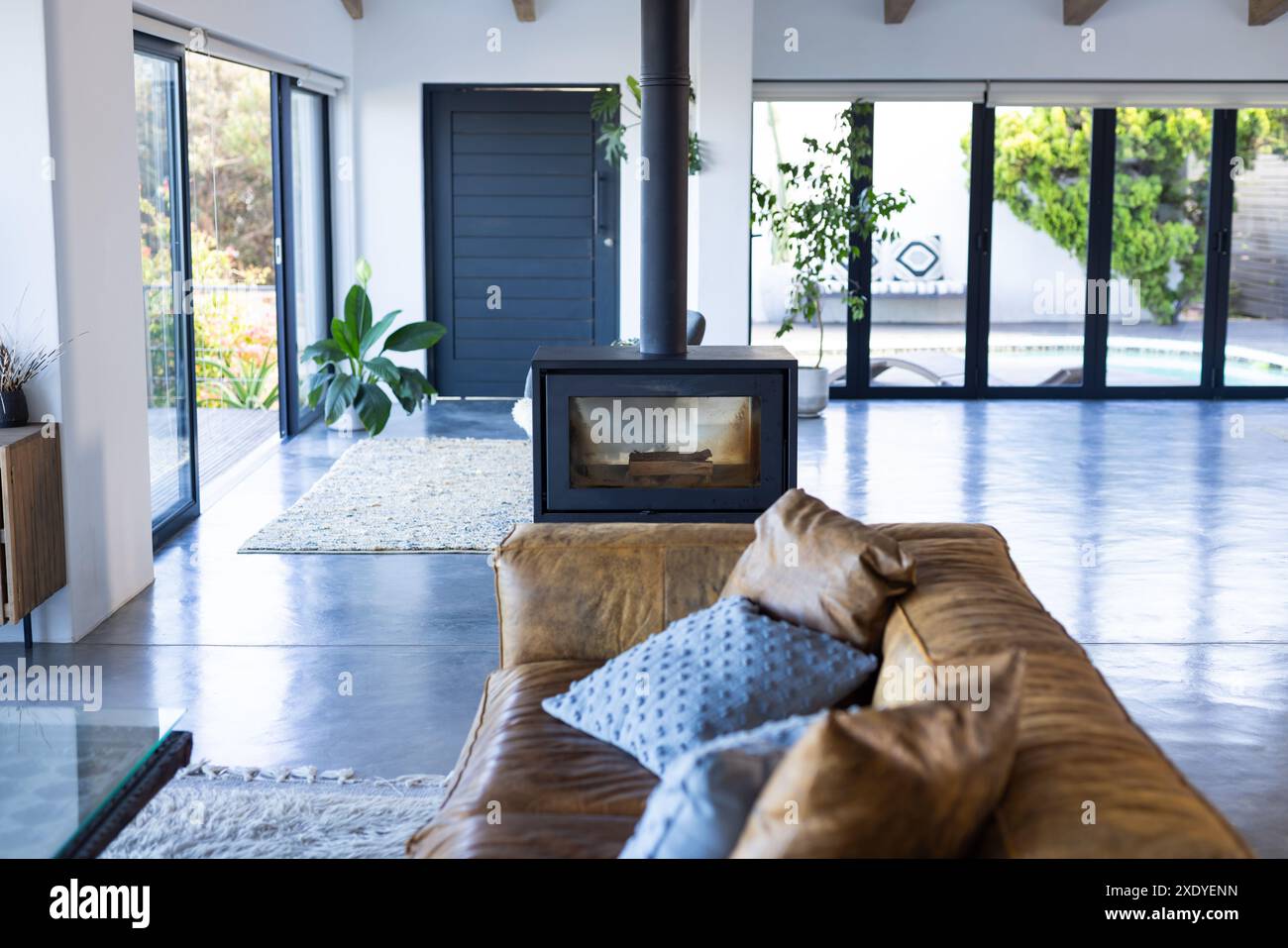 Cozy brown sofa in modern living room with fireplace, large windows ...