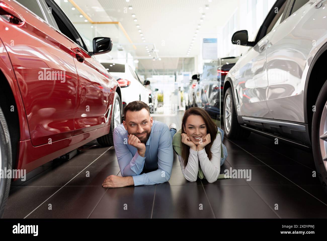 A cheerful charismatic married couple lies in a car dealership between ...