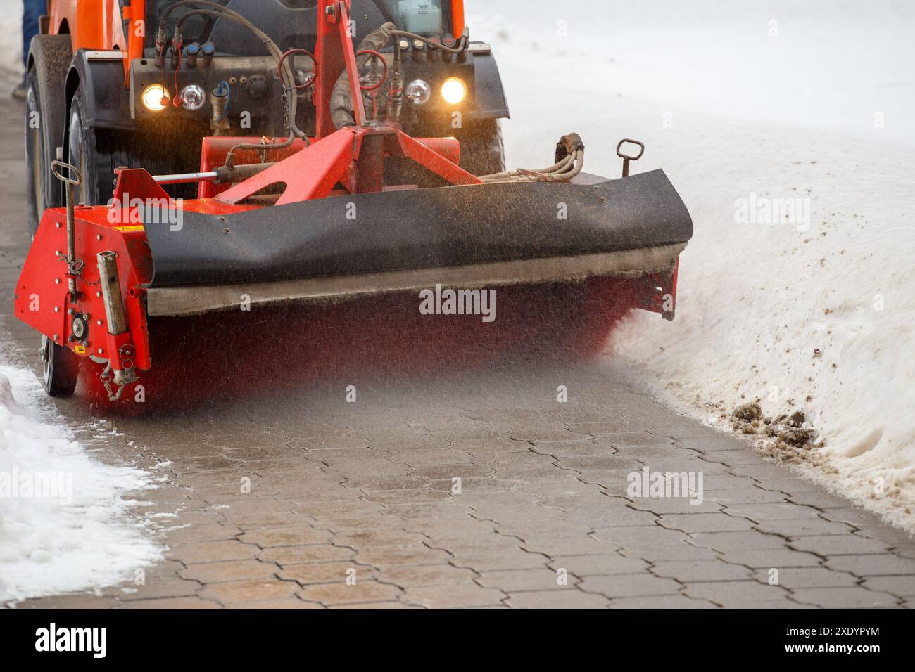 Snow cleaning. Snow removal tractor clearing snow from pavement with ...