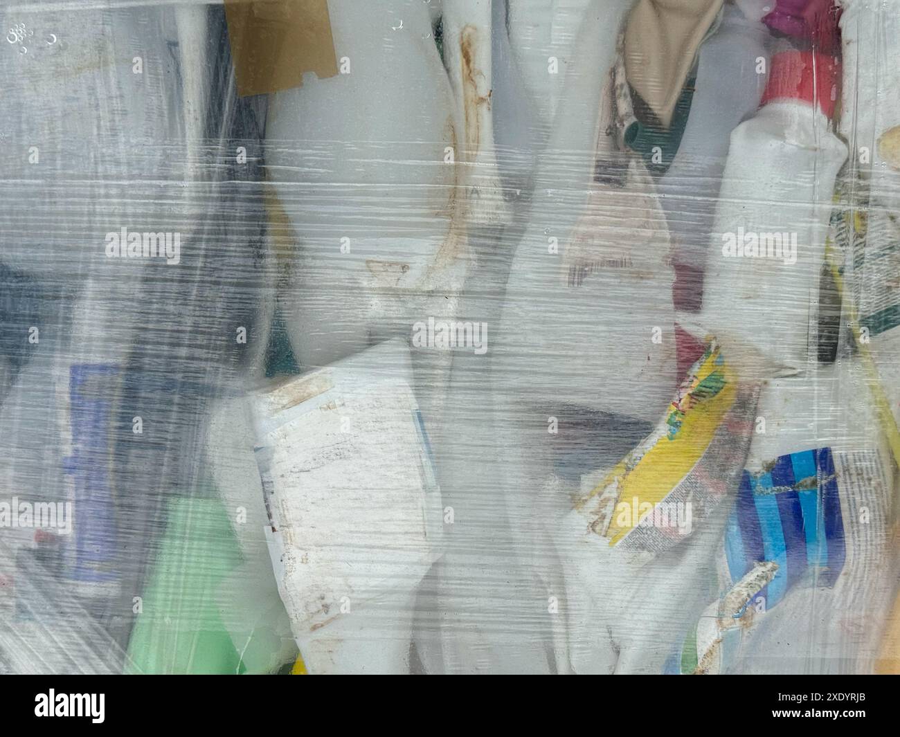 A tightly packed bale of mixed plastic bottles and containers wrapped ...