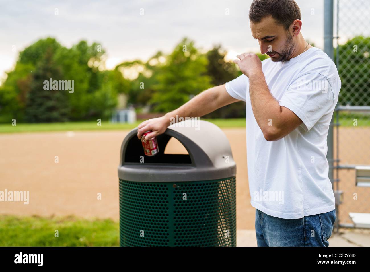 Young man throwing trash in litter bin outdoors. Recycling Stock Photo ...