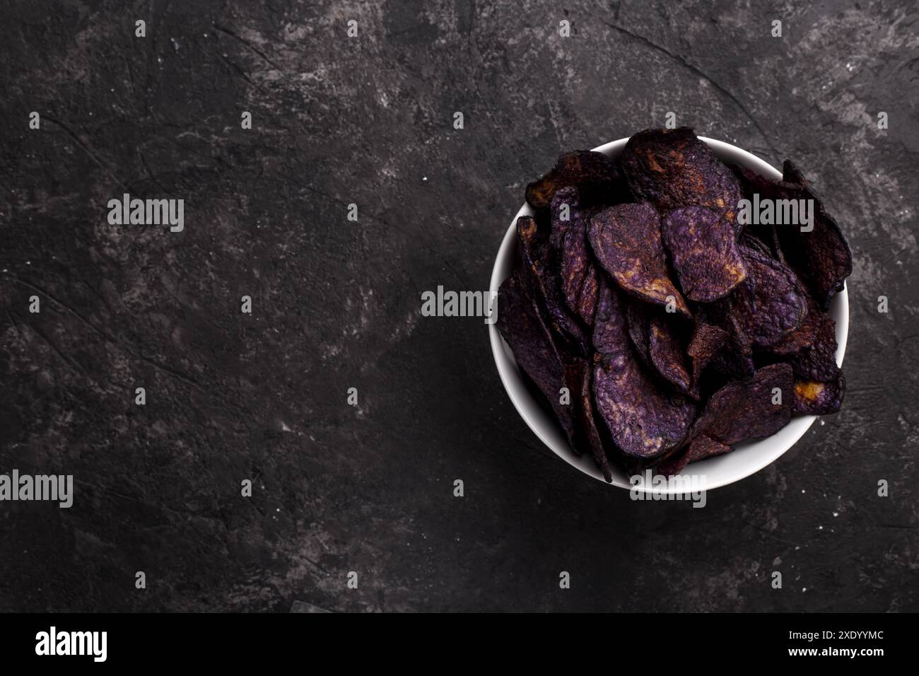 Purple sweet potato chips on black stone background Stock Photo - Alamy