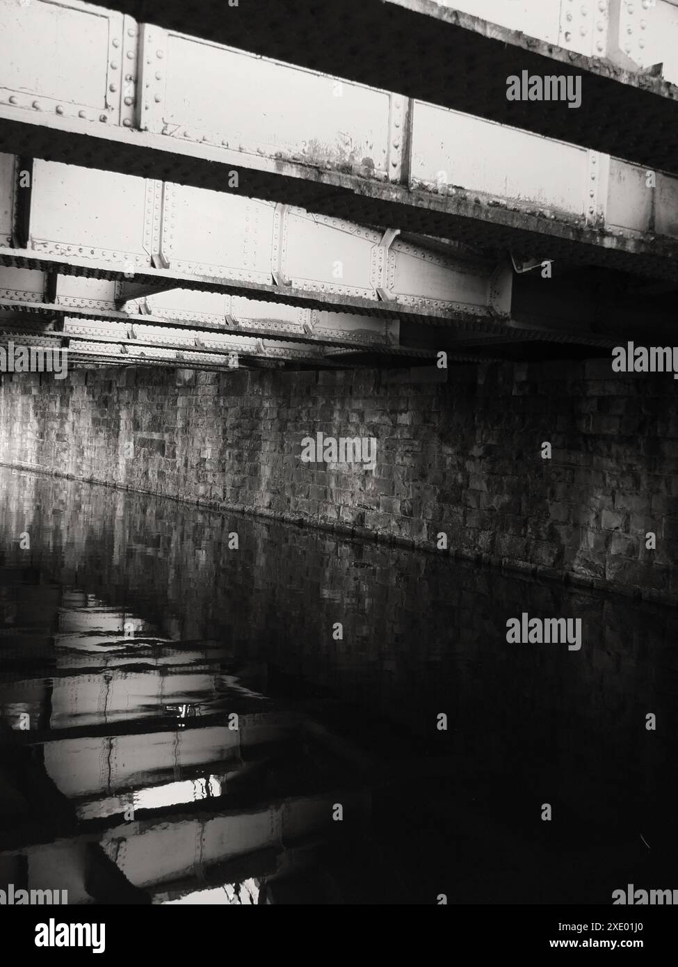 monochrome view under an old low steel girder bridge crossing the leeds ...
