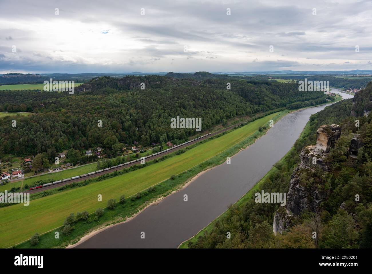 A river with a train passing by. The train is long and it is moving ...