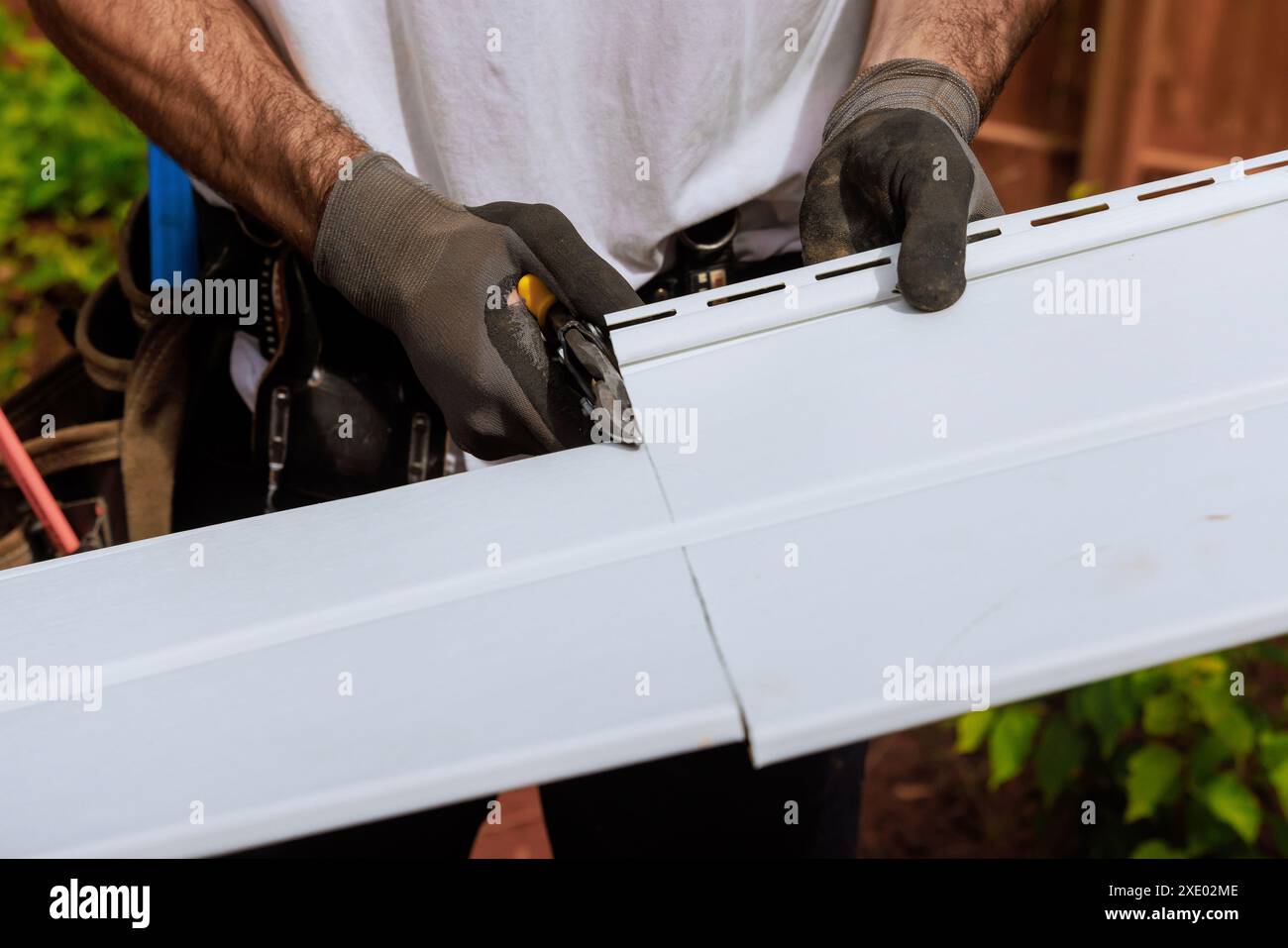 In course of construction, craftsman cuts vinyl siding panels to ...