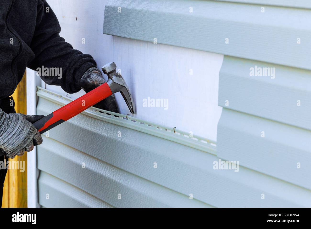 As part of an exterior house renovation, damaged plastic siding is ...