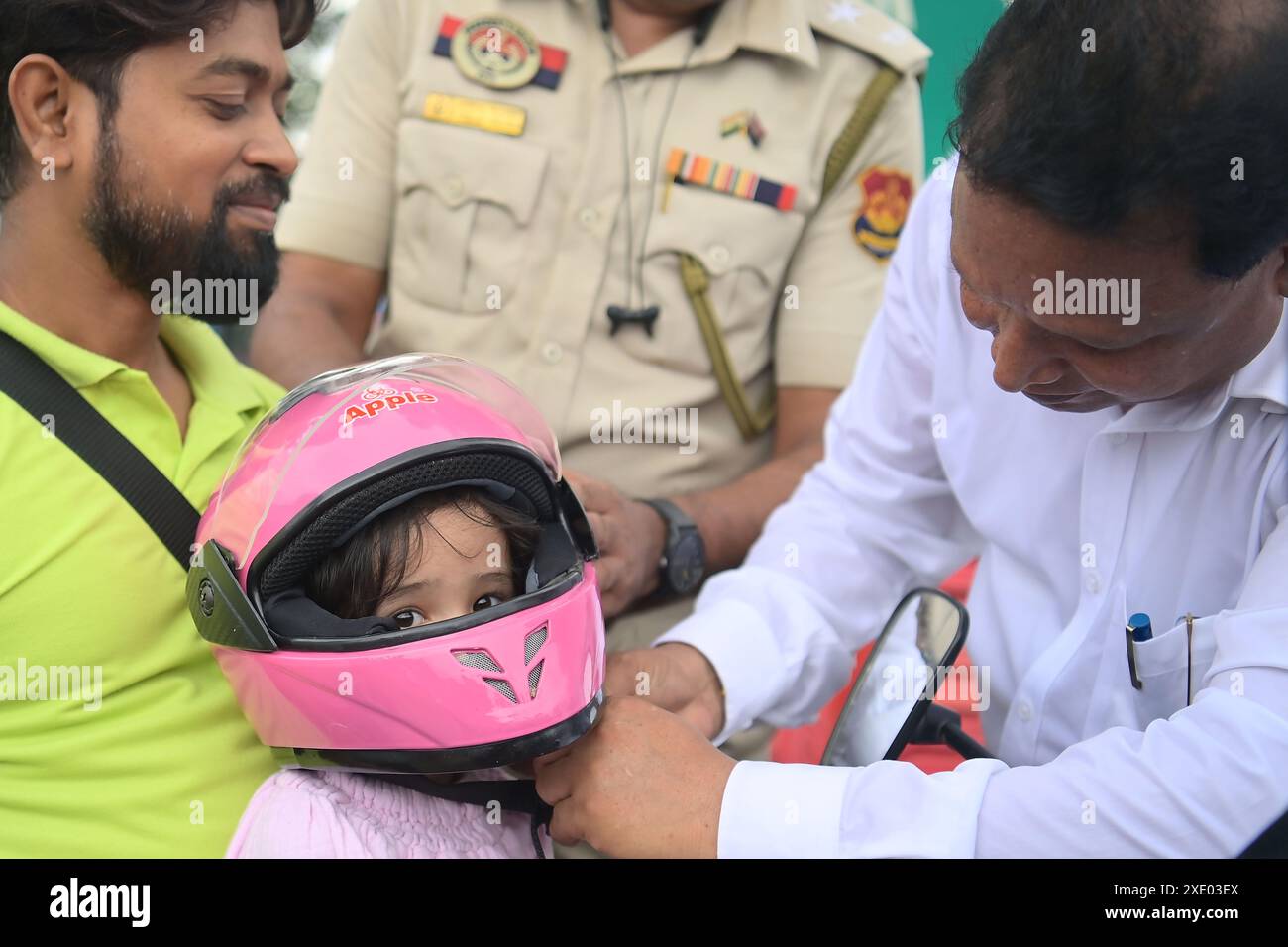 A traffic official puts a helmet on a kid who is riding on a motorcycle ...