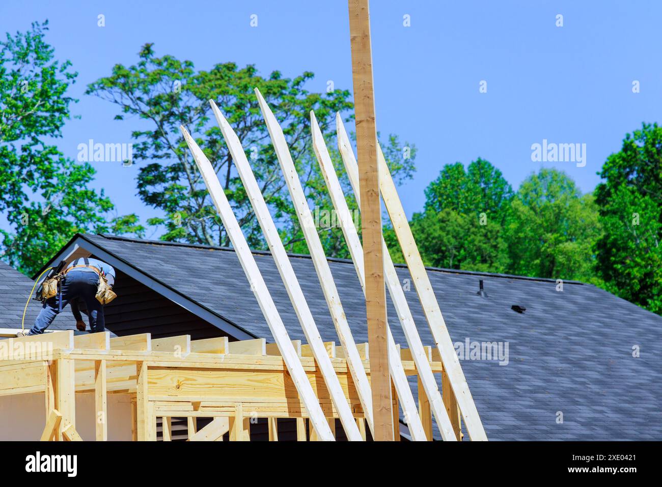 Worker installing beams using an air hammer while nailing wooden plank ...